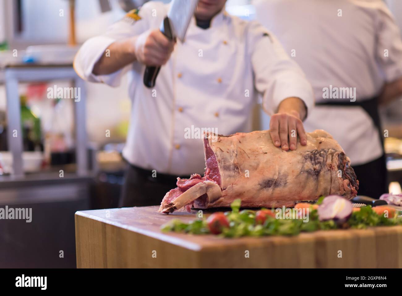 chef using ax while cutting big piece of beef on wooden board in ...