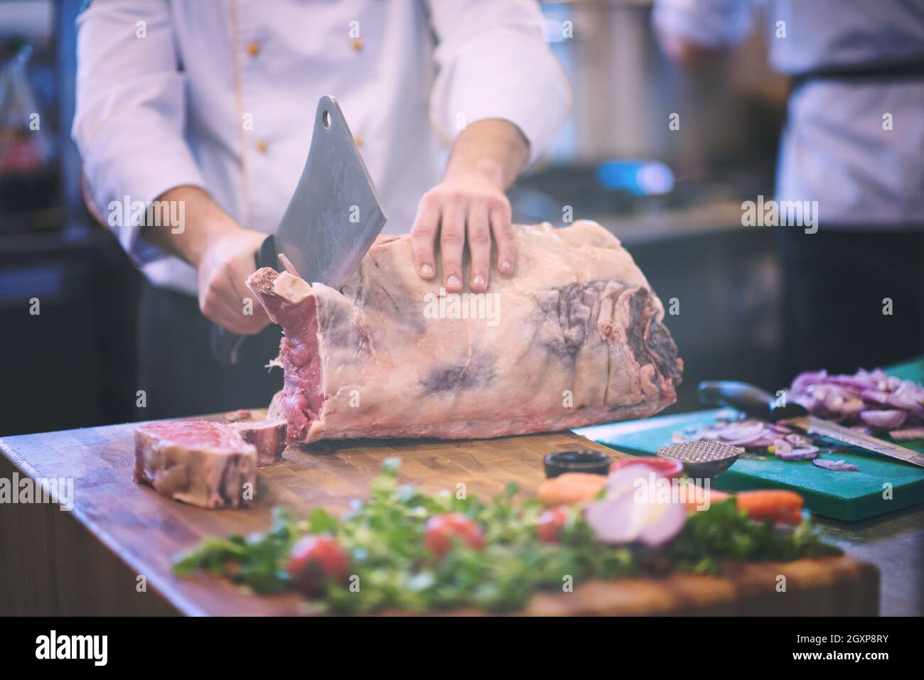 chef using ax while cutting big piece of beef on wooden board in ...