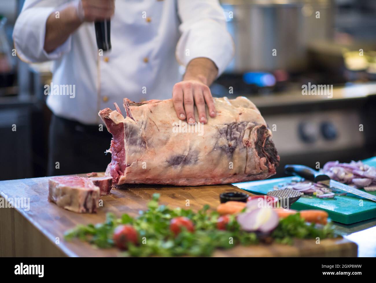 chef using ax while cutting big piece of beef on wooden board in ...