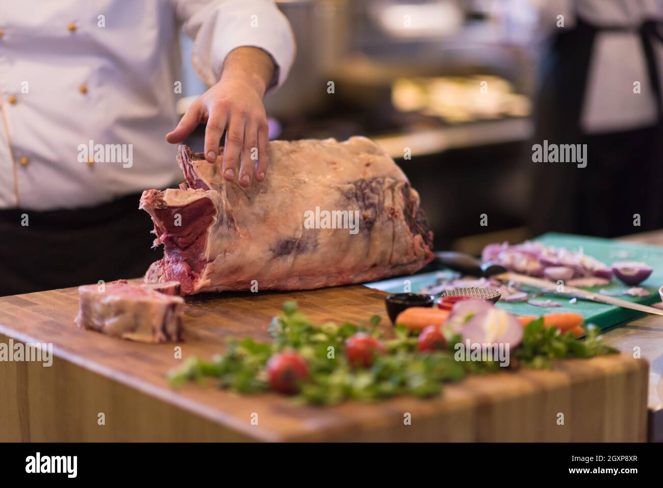 chef using ax while cutting big piece of beef on wooden board in ...