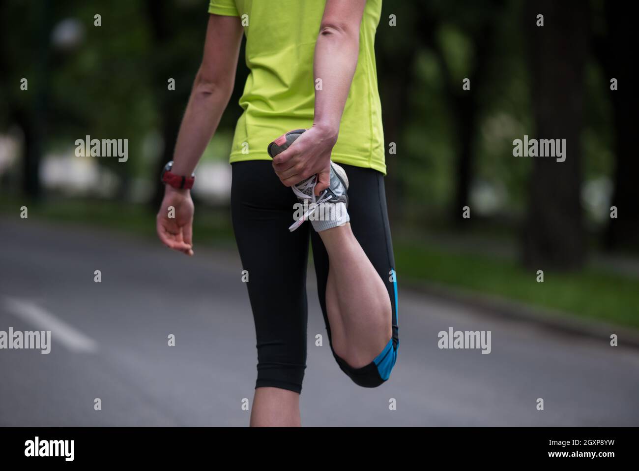 healthy female runner warming up and stretching in city park before ...