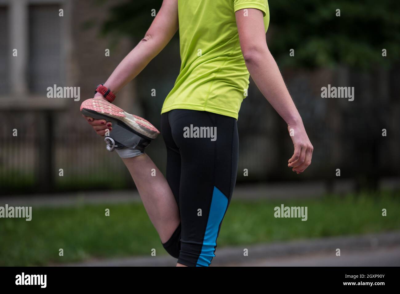 healthy female runner warming up and stretching in city park before ...