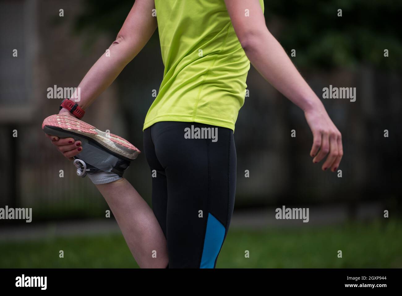 healthy female runner warming up and stretching in city park before ...