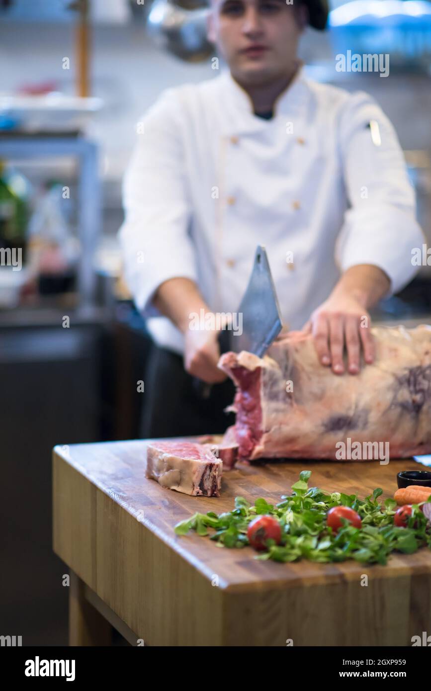 chef using ax while cutting big piece of beef on wooden board in ...