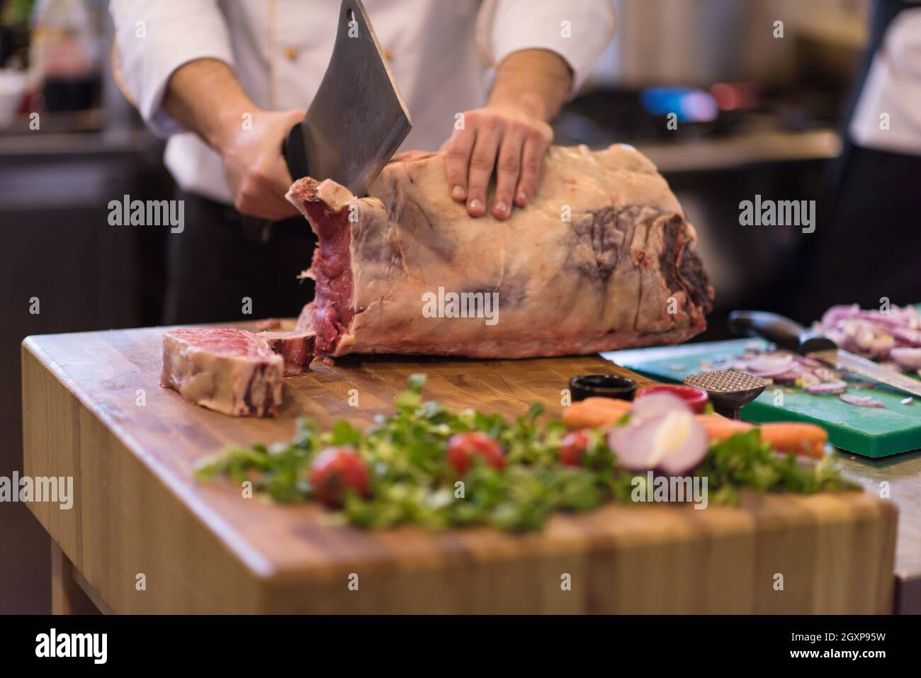 chef using ax while cutting big piece of beef on wooden board in ...