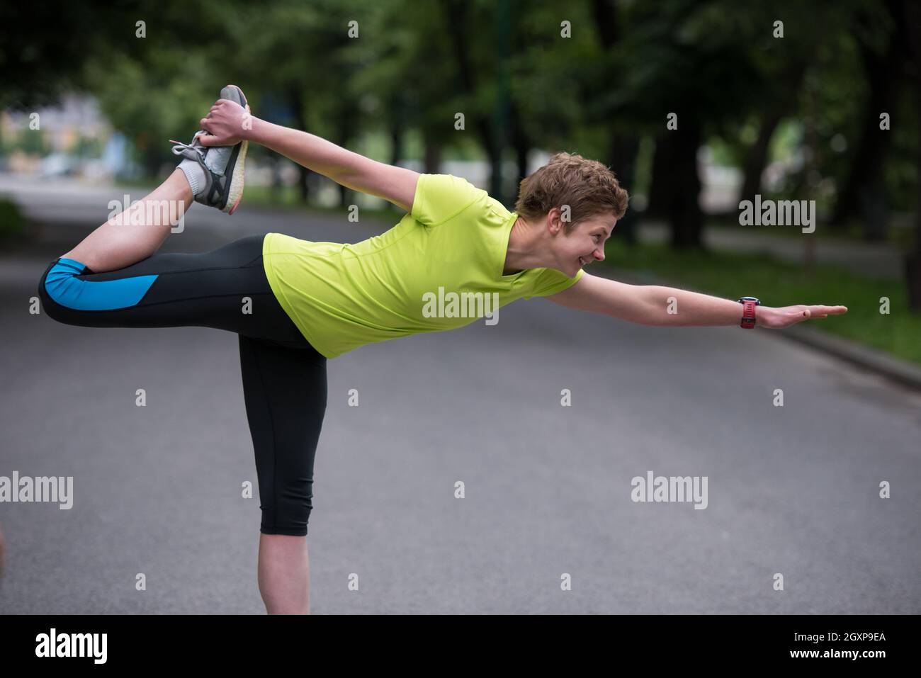 healthy female runner warming up and stretching in city park before ...