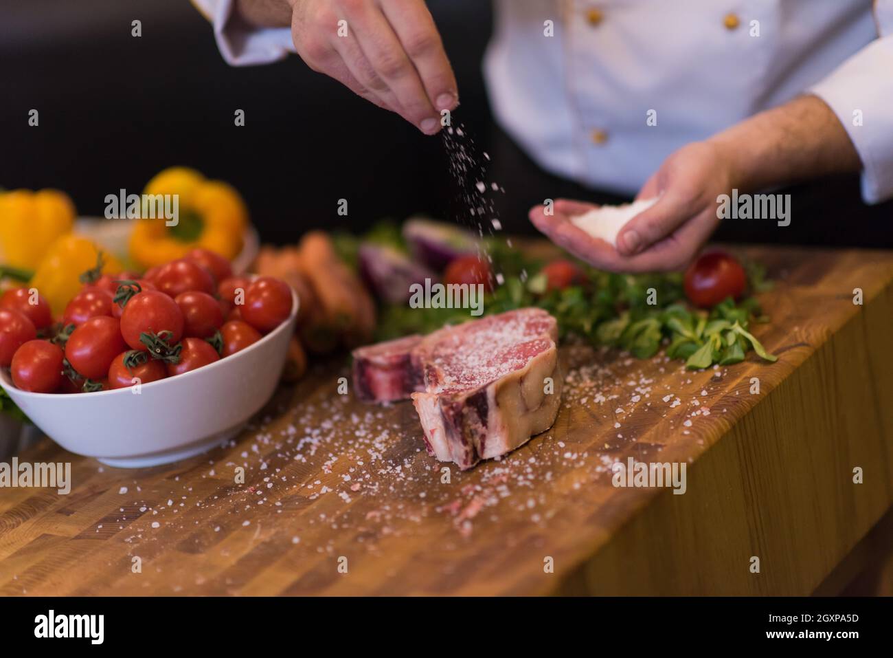 Master Chef hands putting salt on juicy slice of raw steak with ...