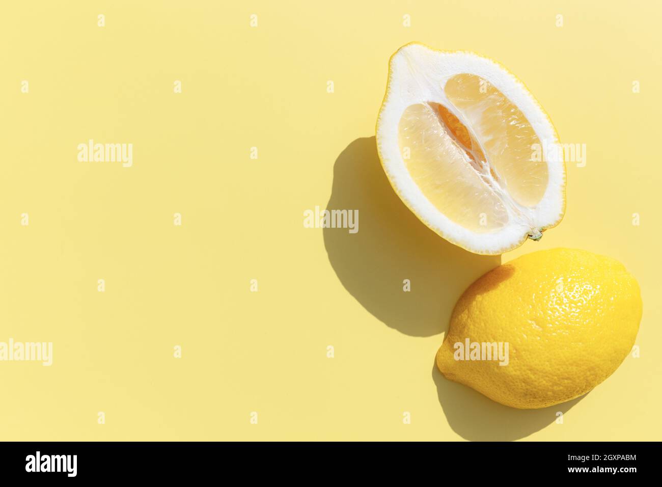 Two halved cuts of lemon with shadow on yellow background. Healthy ...