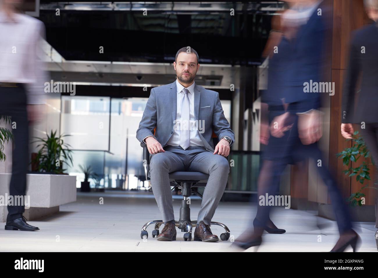 business man sitting in office chair, people group passing by: Concept ...