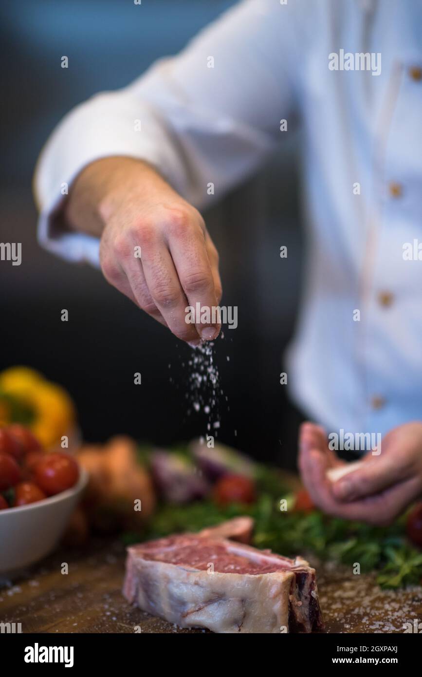 Master Chef hands putting salt on juicy slice of raw steak with ...