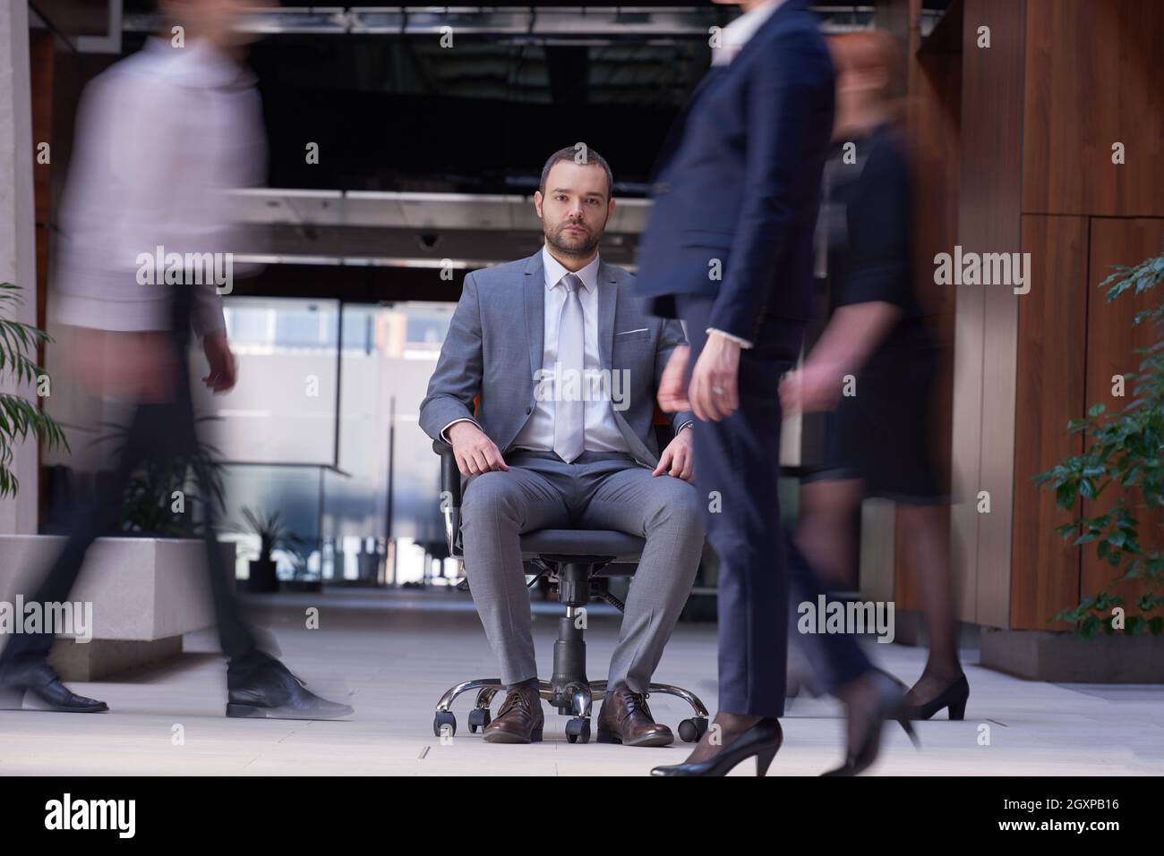business man sitting in office chair, people group passing by: Concept ...
