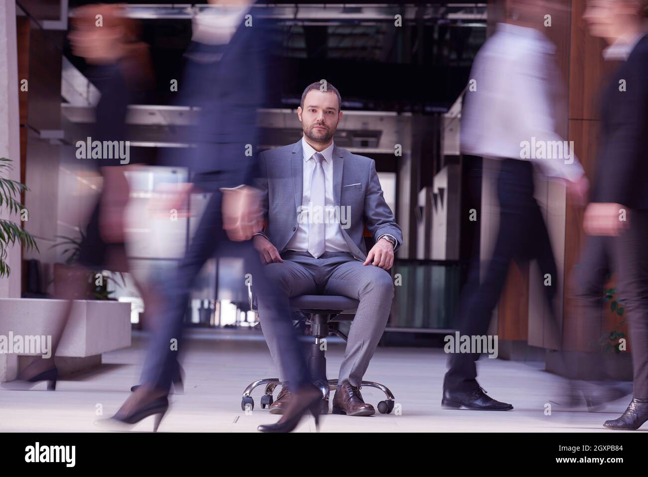 business man sitting in office chair, people group passing by: Concept ...