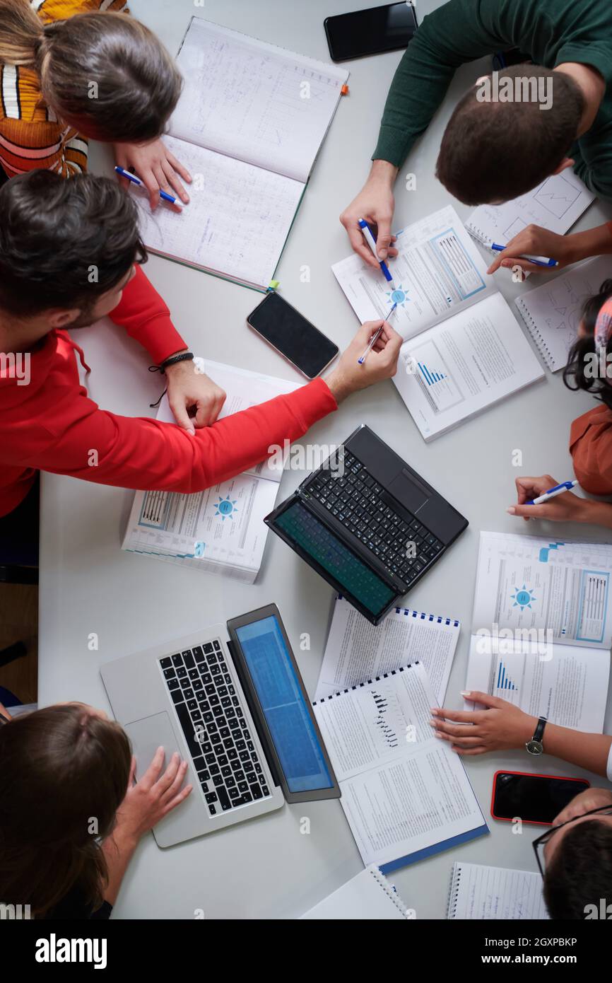 Top view of university students sitting at a table studying and working ...