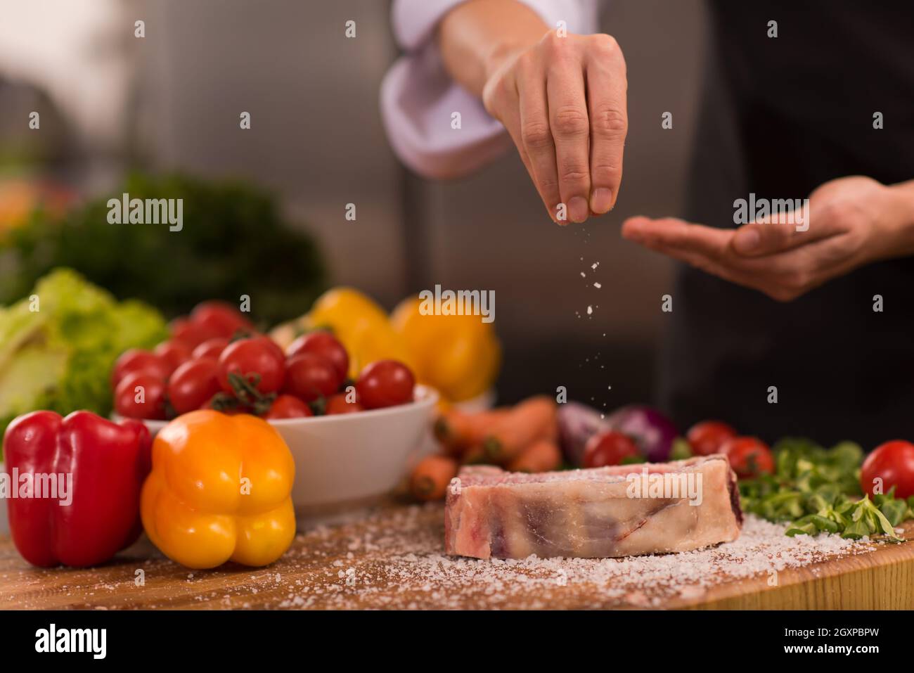 Master Chef hands putting salt on juicy slice of raw steak with ...