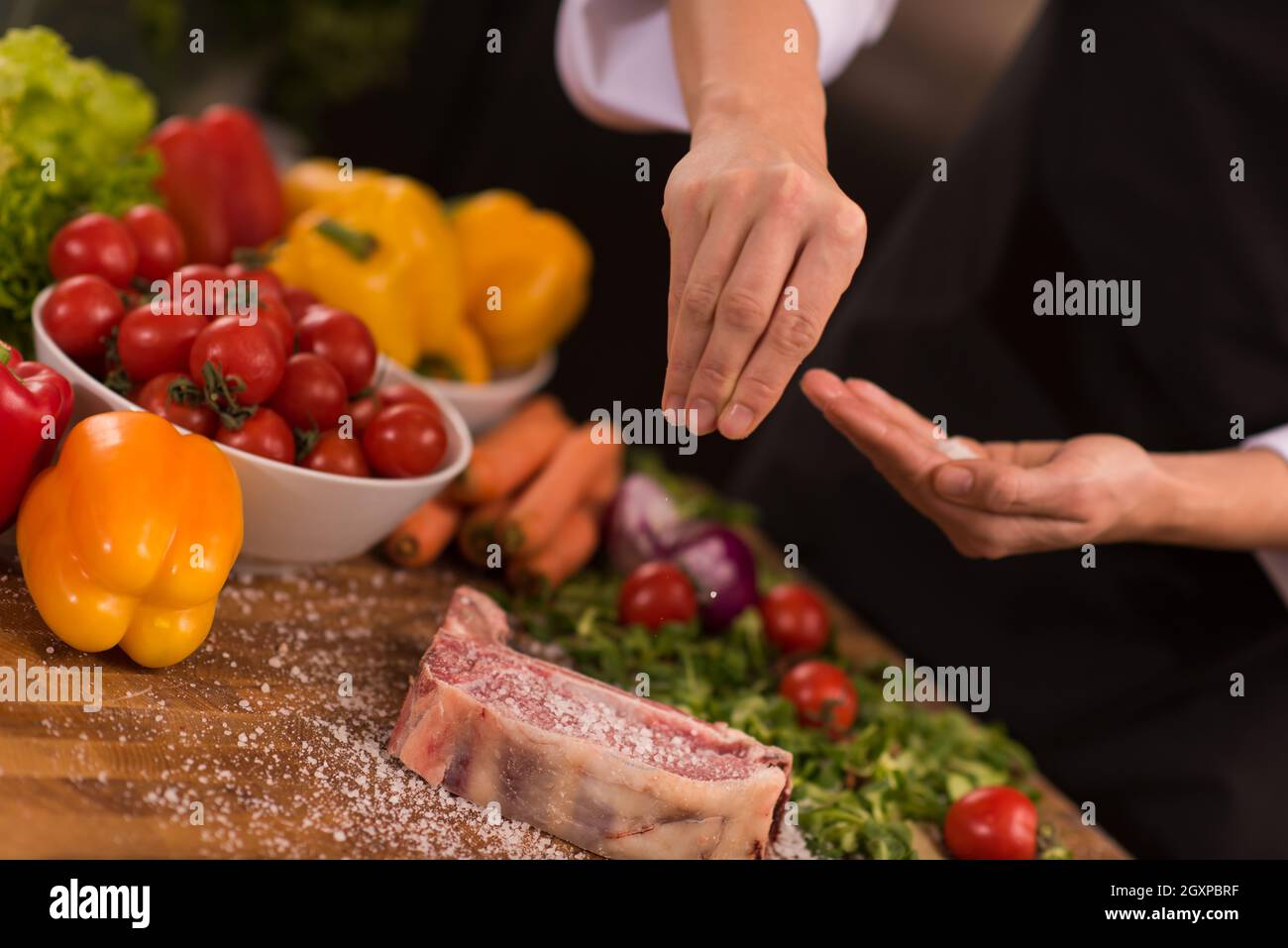 Master Chef hands putting salt on juicy slice of raw steak with ...