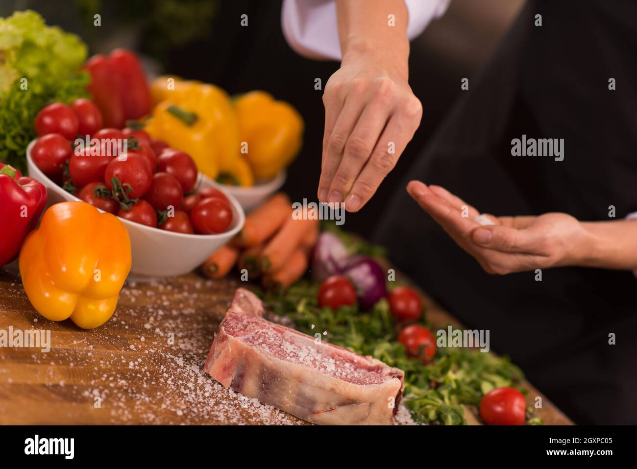 Master Chef hands putting salt on juicy slice of raw steak with ...