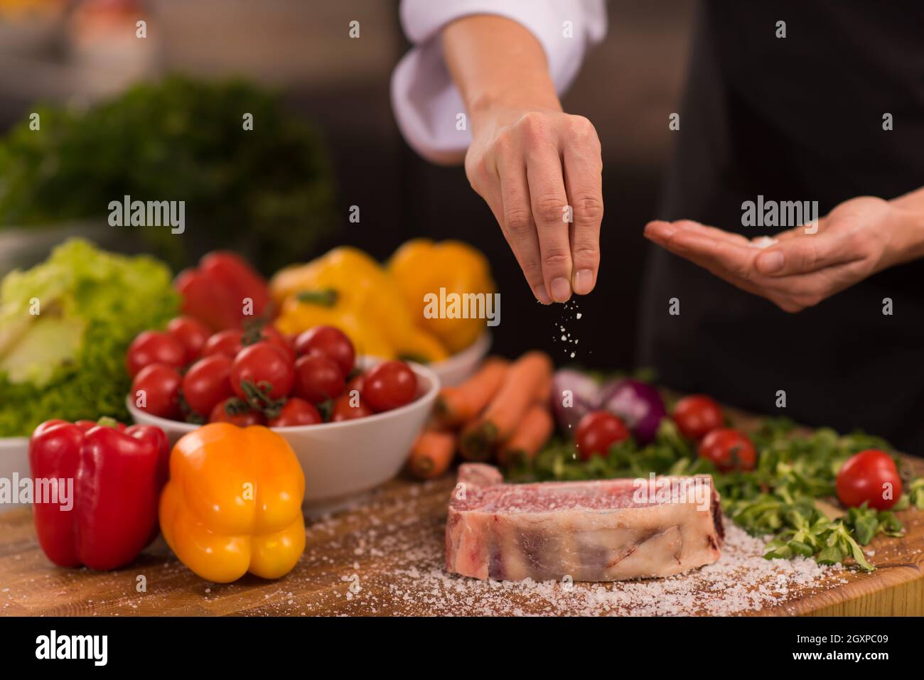 Master Chef hands putting salt on juicy slice of raw steak with ...
