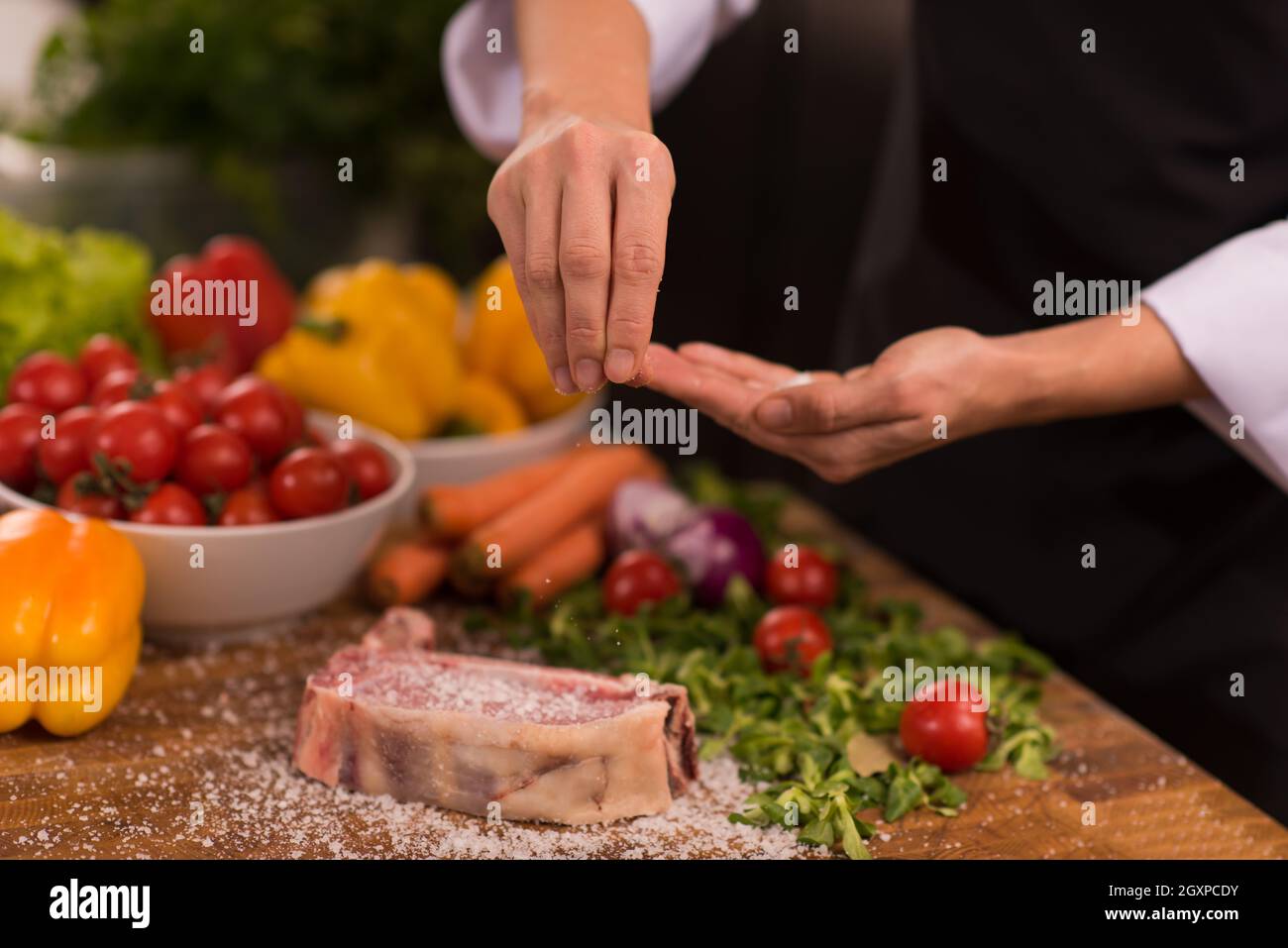 Master Chef hands putting salt on juicy slice of raw steak with ...
