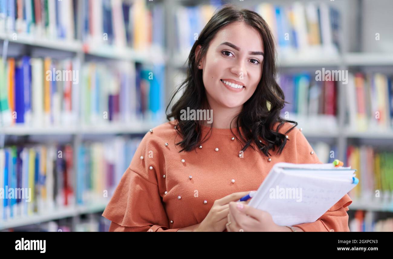 Reading a book in library. Young attractive librarian reading a book ...