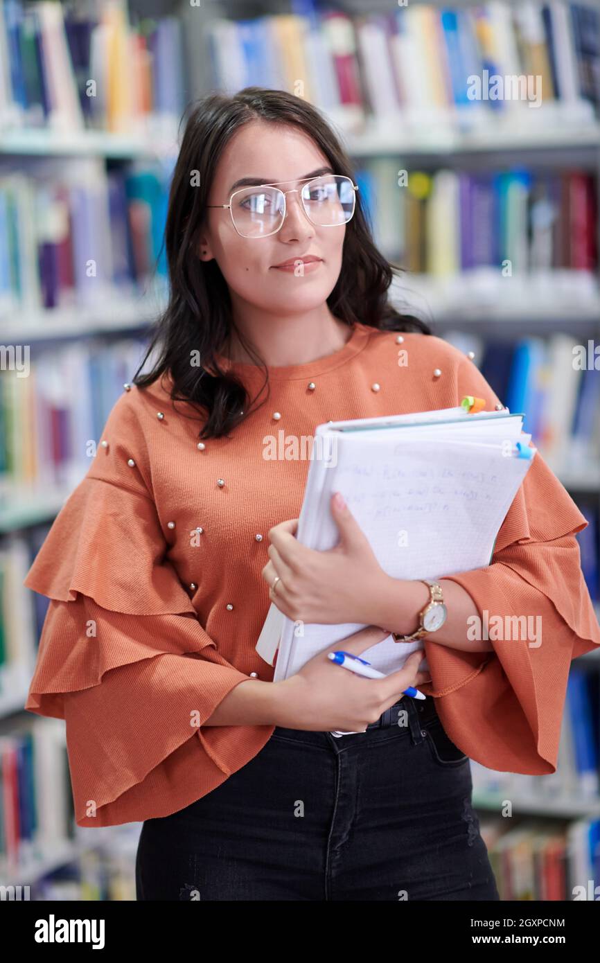 Reading a book in library. Young attractive librarian reading a book ...