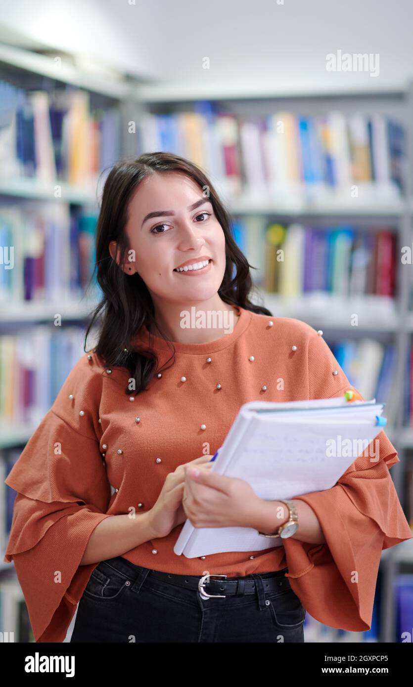 Reading a book in library. Young attractive librarian reading a book ...