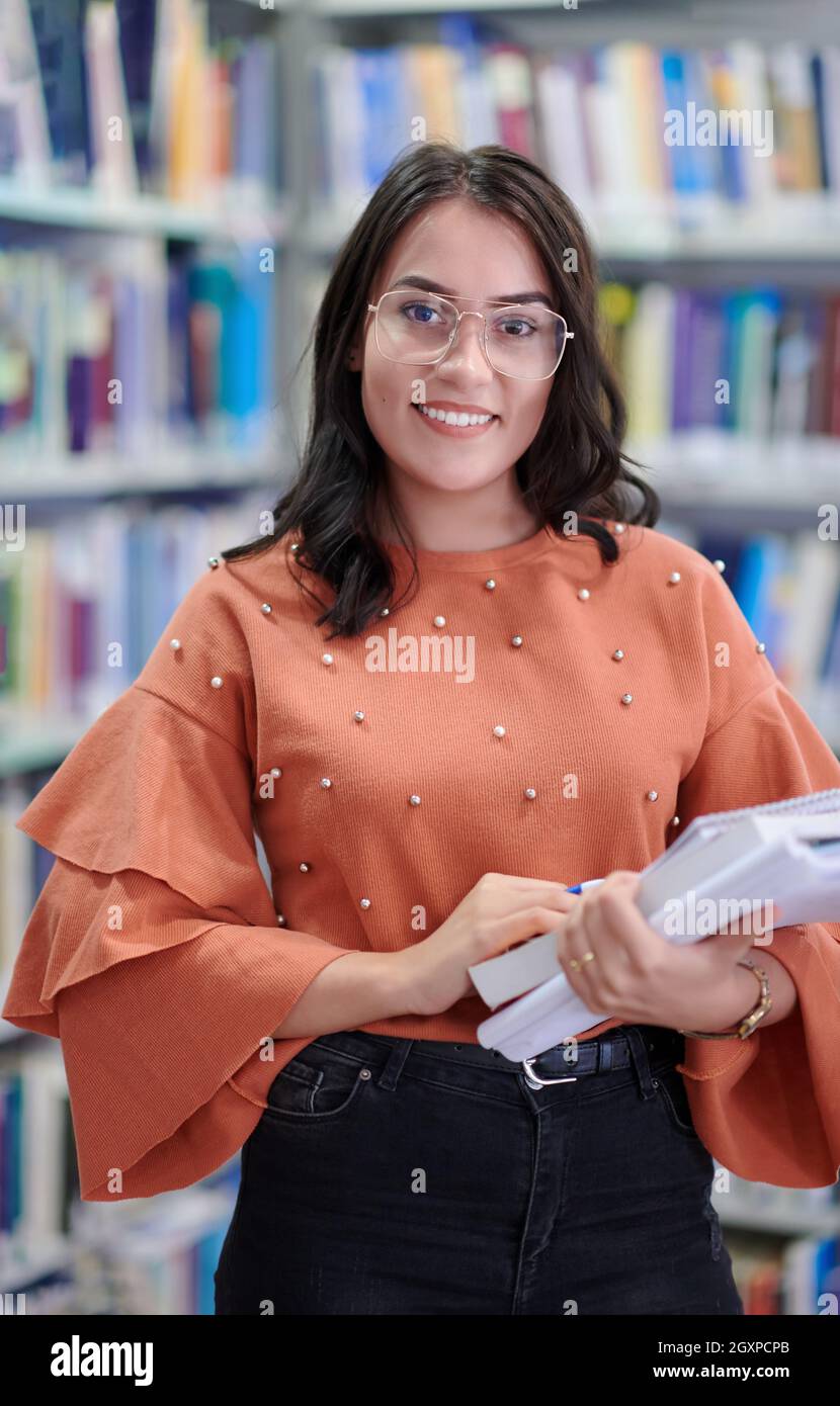 Reading a book in library. Young attractive librarian reading a book ...