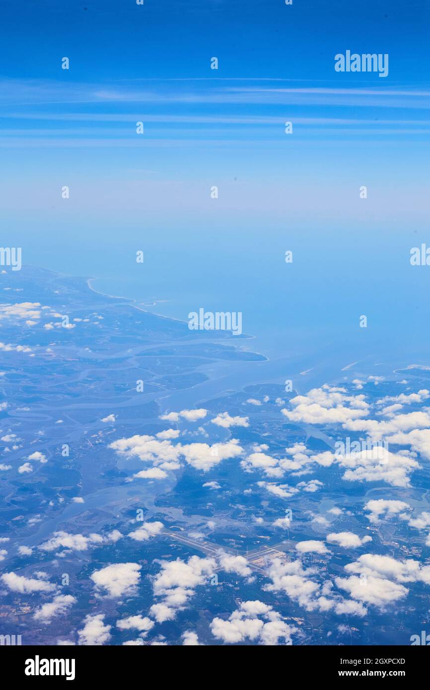 Airplane view of clouds and blue sky with land in distance Stock Photo ...
