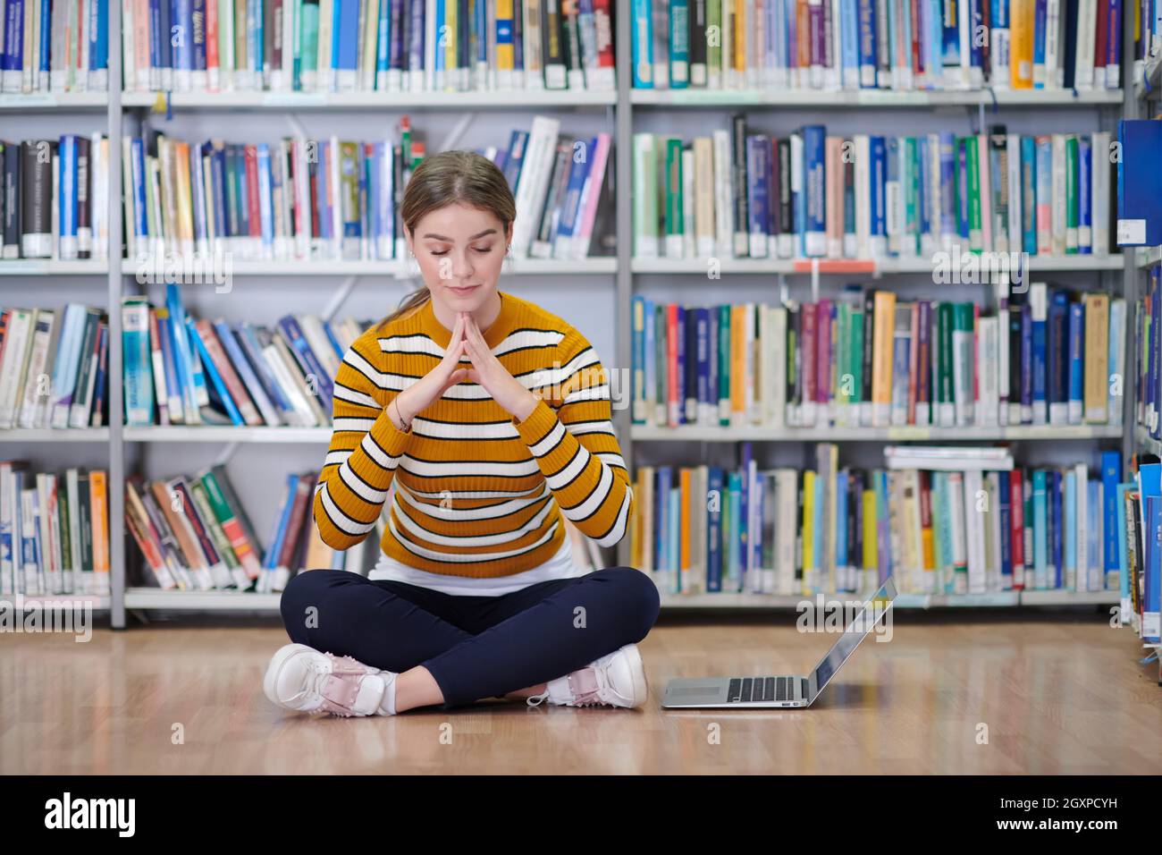 Woman student taking notes from a book at library. Young woman sitting ...