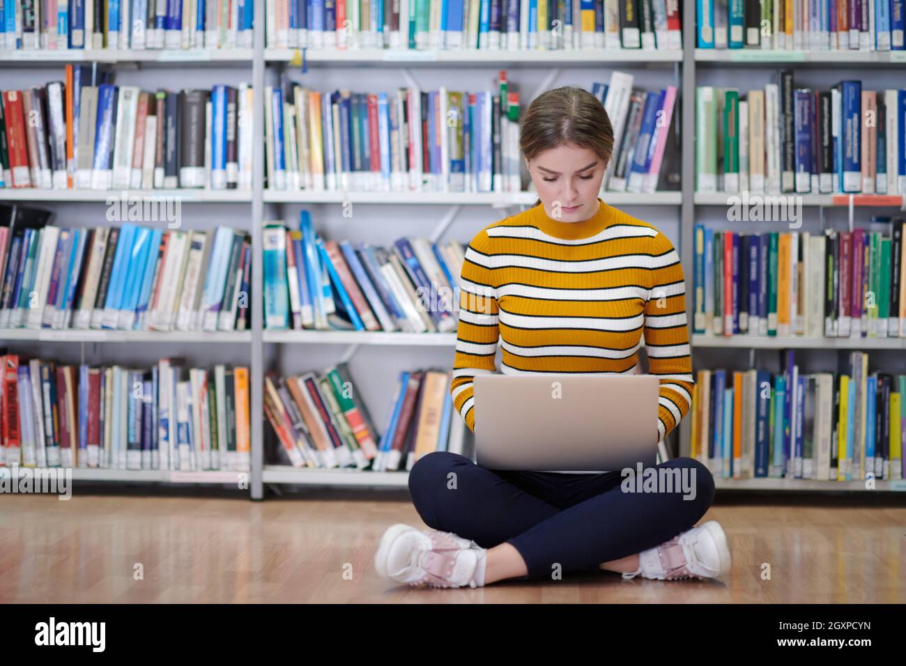 Woman student taking notes from a book at library. Young woman sitting ...