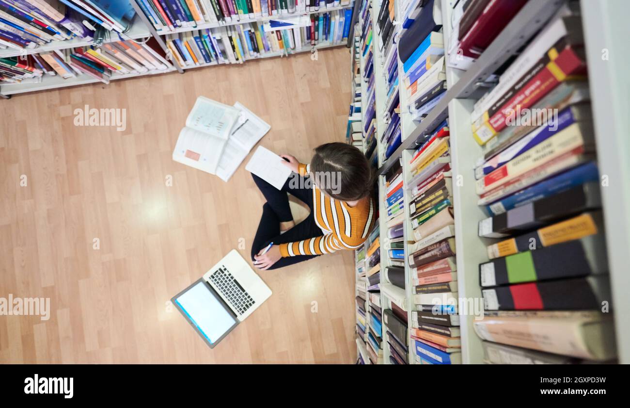 student taking notes from a book at library. Young woman sittingin in ...