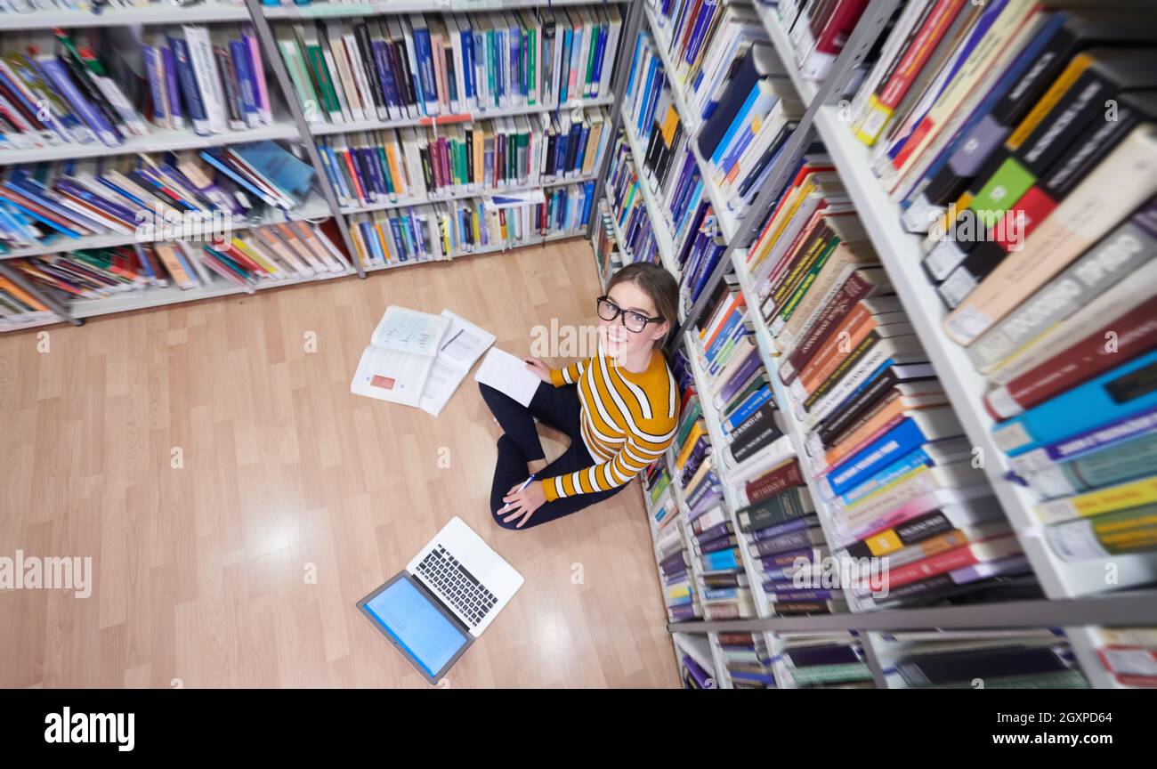 student taking notes from a book at library. Young woman sittingin in ...