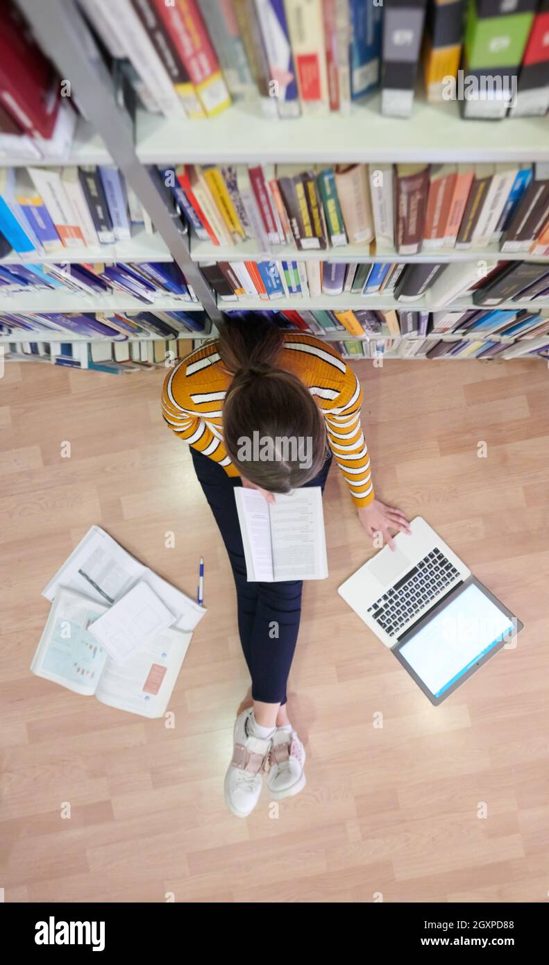 student taking notes from a book at library. Young woman sittingin in ...