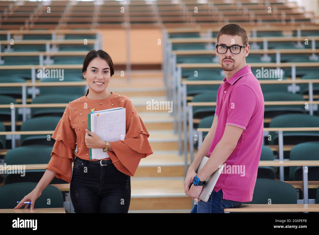 students pose in an empty classroom while holding a laptop and notebook ...
