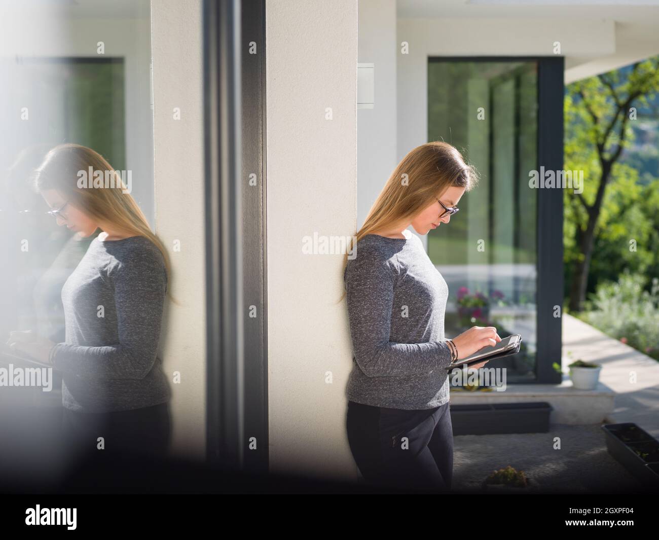 beautiful young women using tablet computer in front of her luxury home ...