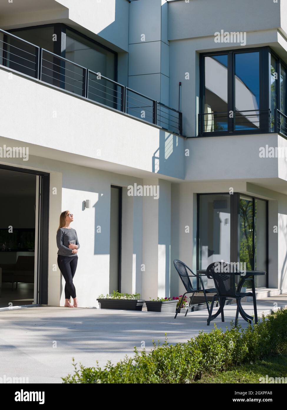 beautiful young women using tablet computer in front of her luxury home ...