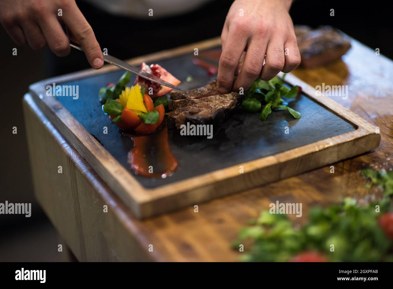 closeup of Chef hands in hotel or restaurant kitchen serving beef steak ...