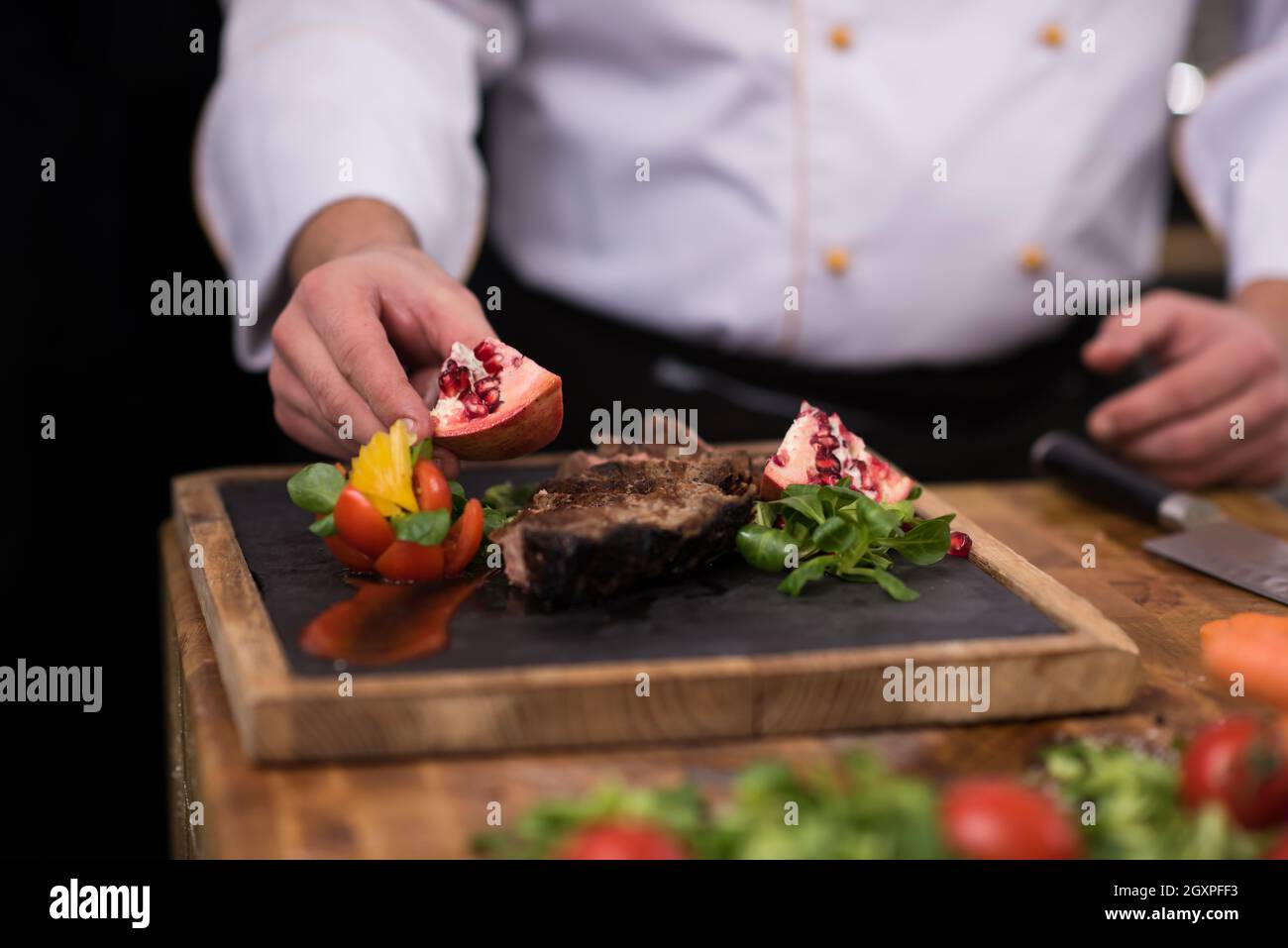 closeup of Chef hands in hotel or restaurant kitchen serving beef steak ...