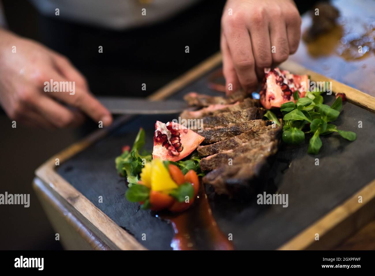 closeup of Chef hands in hotel or restaurant kitchen serving beef steak ...
