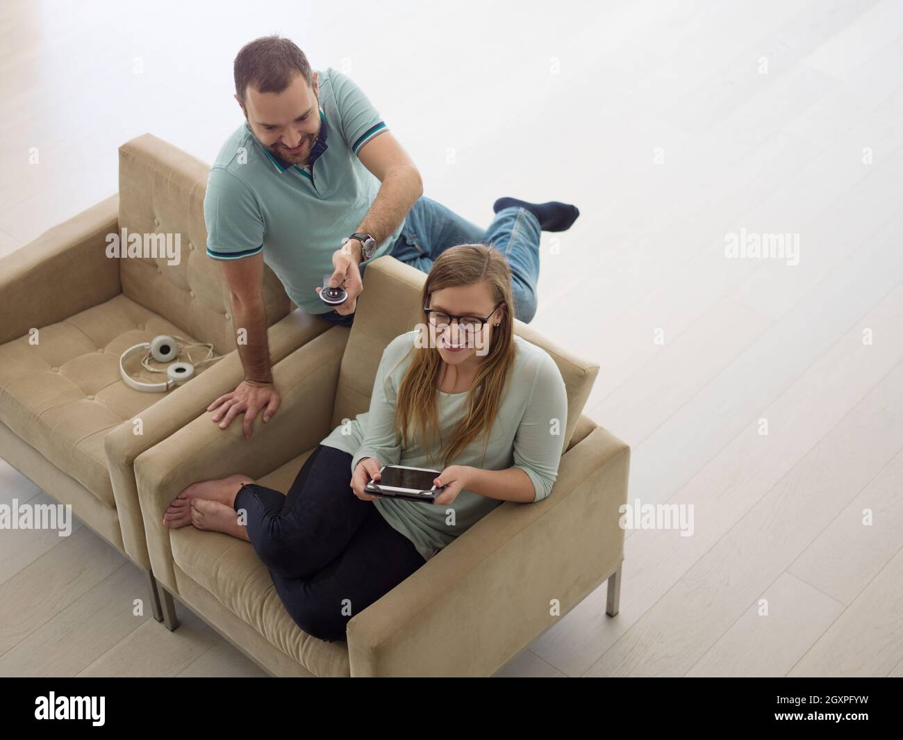 Young couple relaxing at luxurious home with tablet computers reading ...