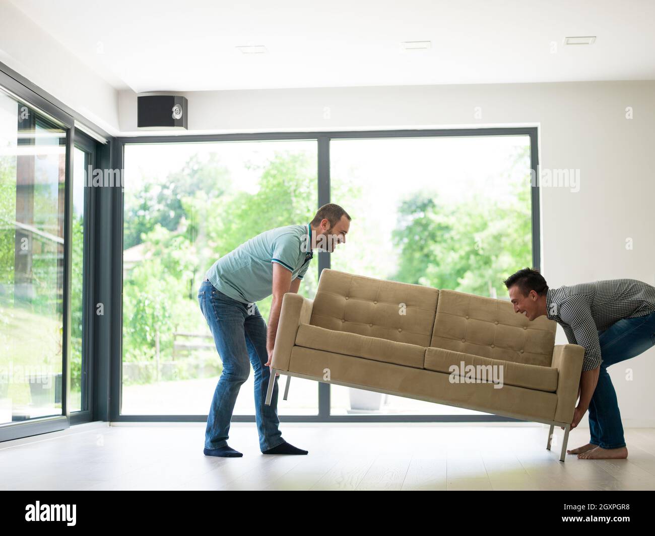 two young men carry the sofa in front of window Stock Photo - Alamy