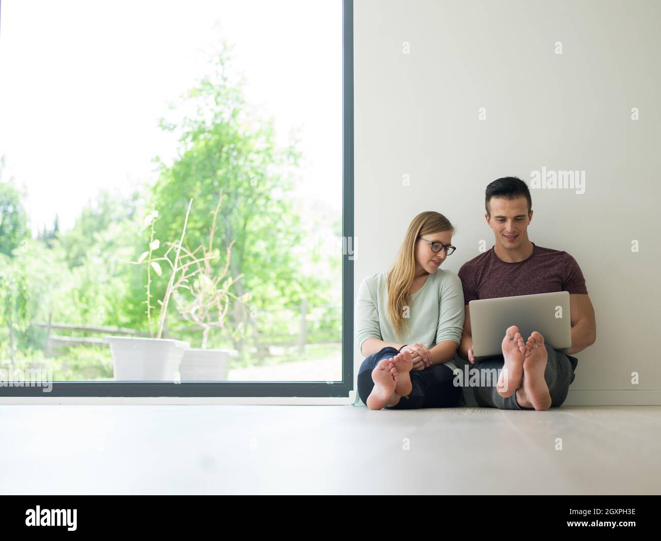 Young couple using laptop computer on the floor at luxury home together ...