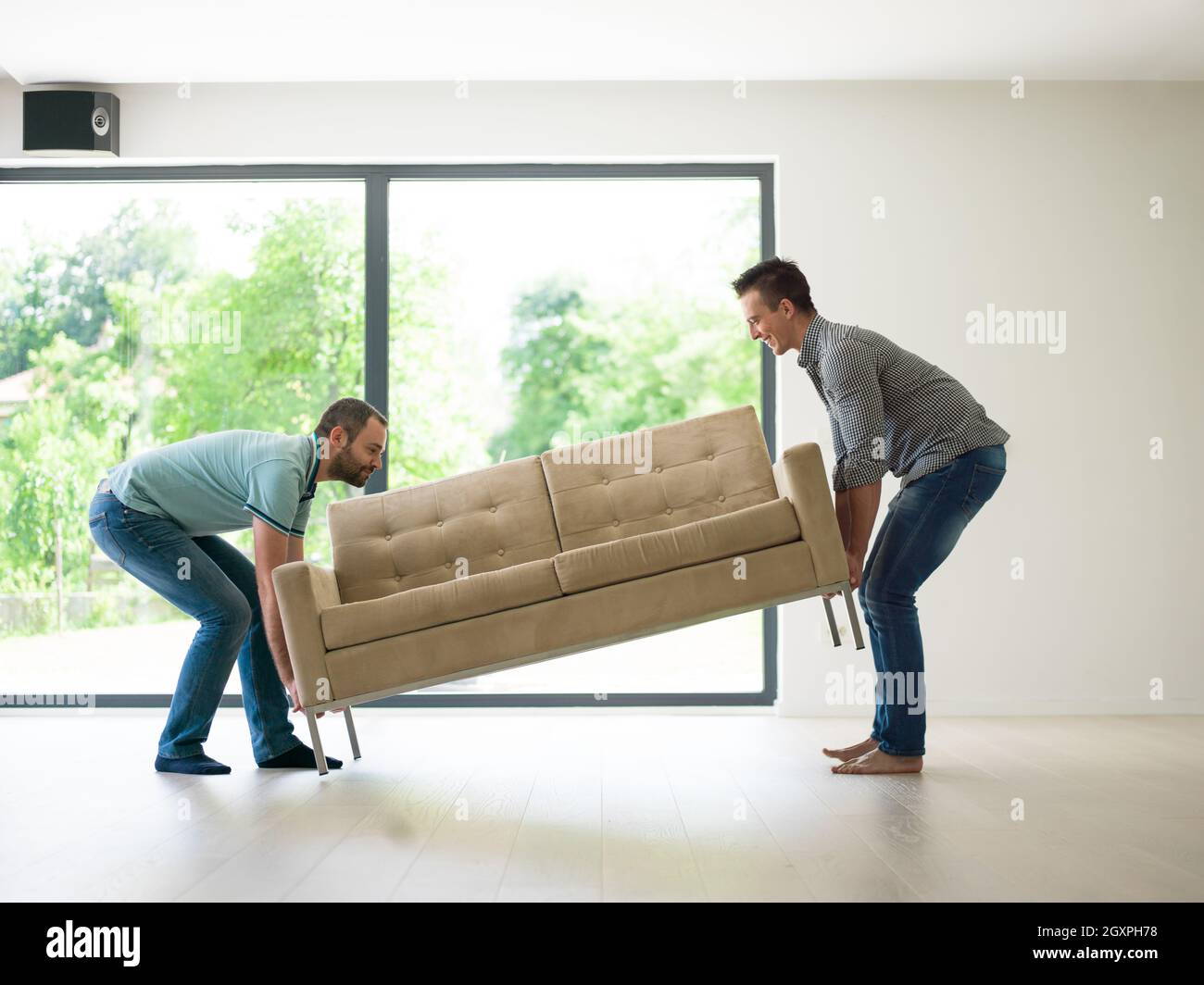 two young men carry the sofa in front of window Stock Photo - Alamy