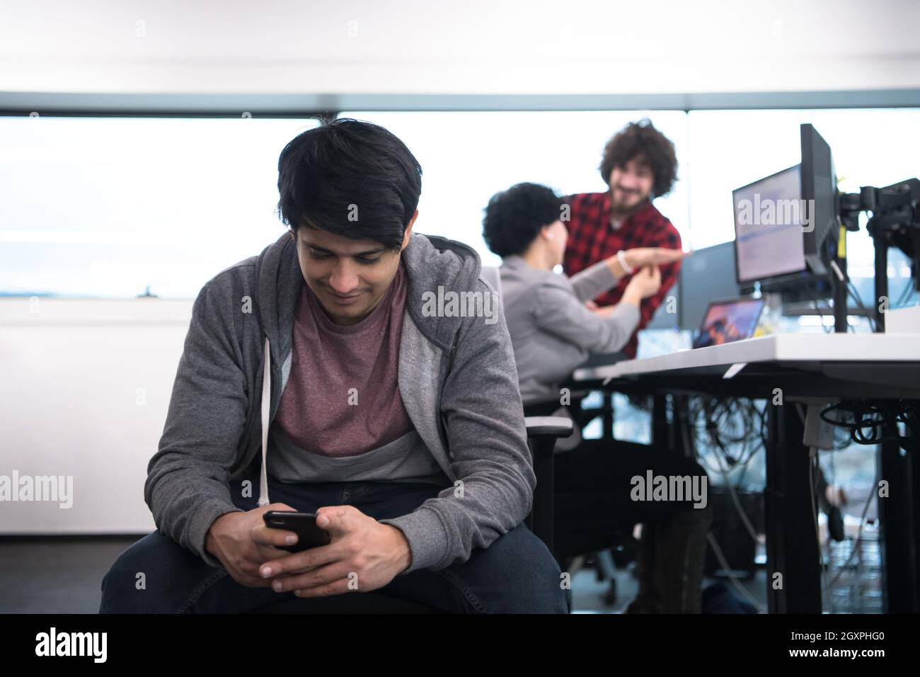 young indian male software developer using mobile phone writing ...