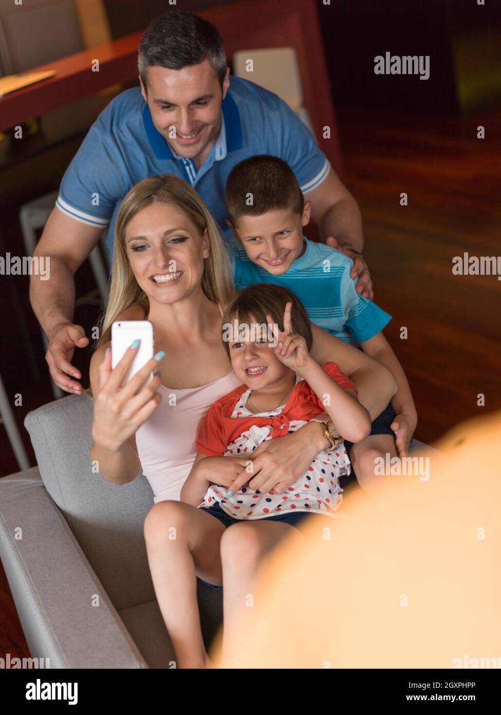 Happy family siting on sofa and using cell phone for video call at home ...