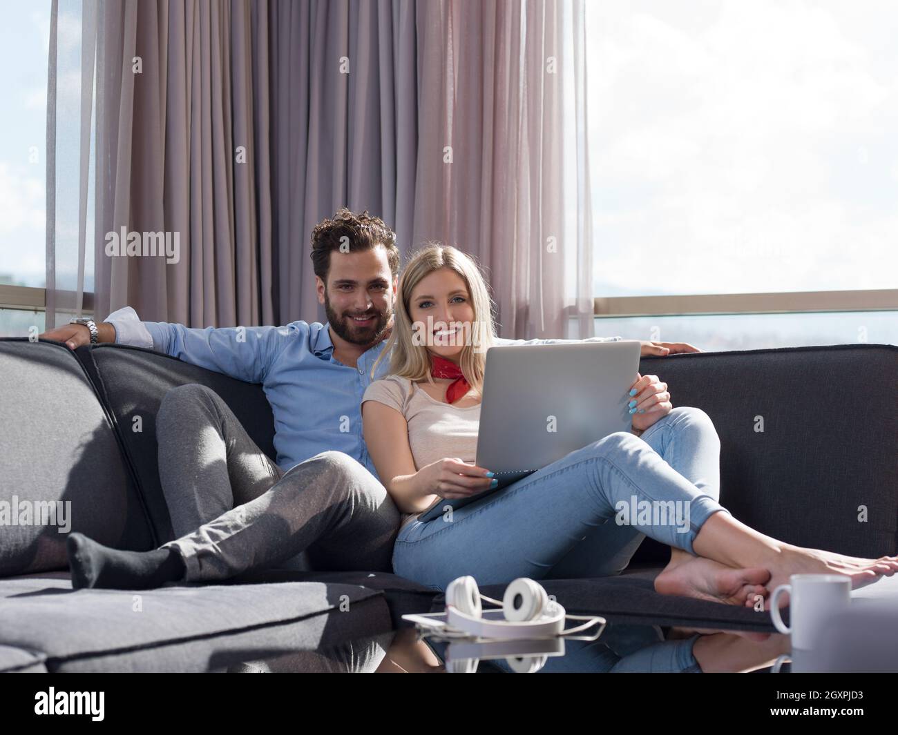 Young couple relaxing at luxury home using laptop computer reading in ...