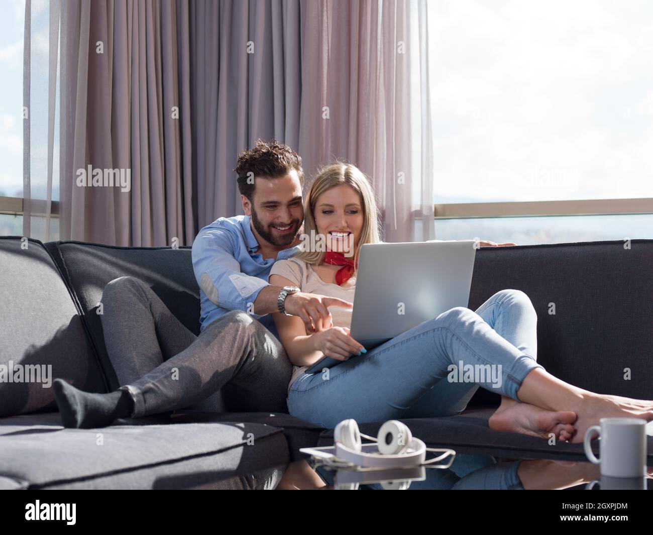 Young couple relaxing at luxury home using laptop computer reading in ...