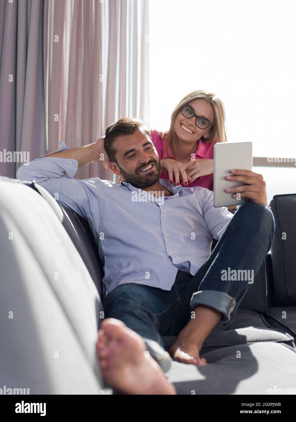 Young couple relaxing at home using tablet computers reading in the ...
