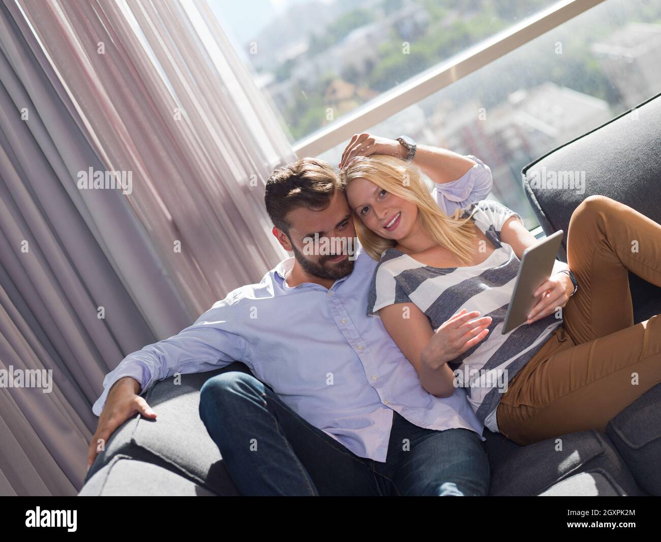 Young couple relaxing at home using tablet computers reading in the ...