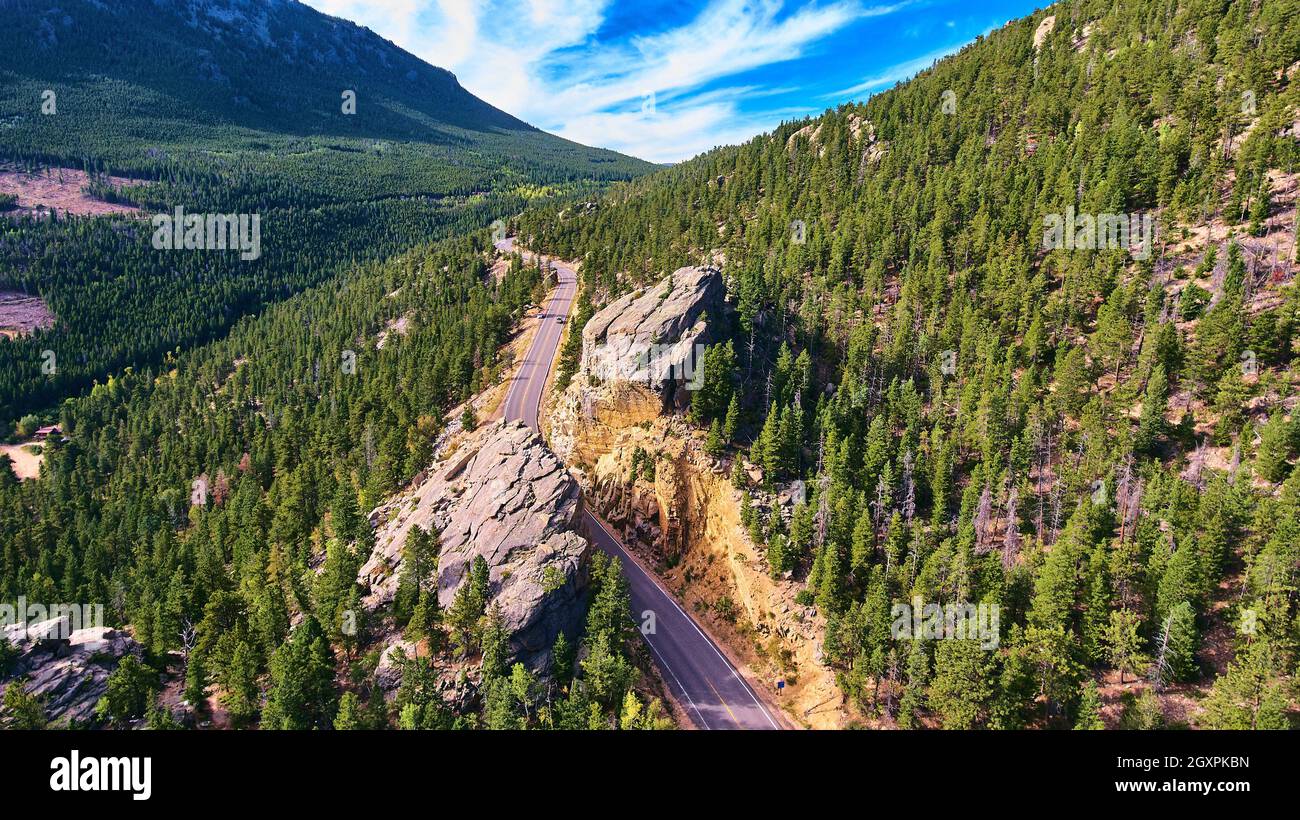 Road cutting through large mountain rock in valley of pine trees Stock ...