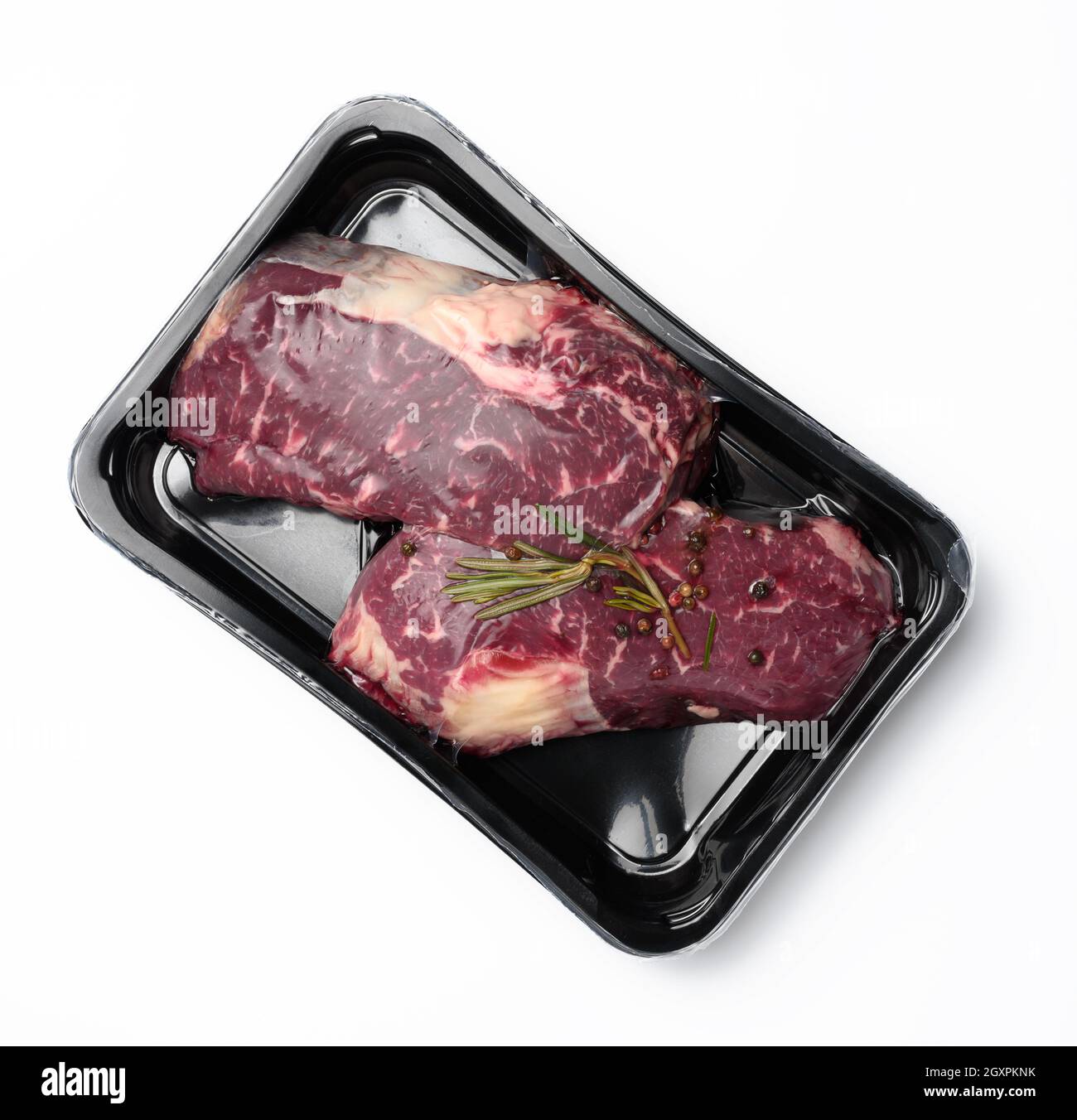 two raw beef steaks in a plastic container with spices and vacuumized ...